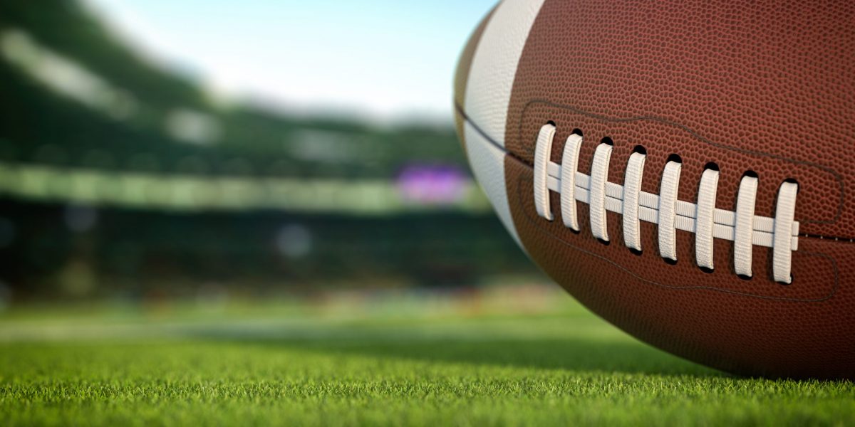 American football ball on grass of football arena | El Sol de la Florida
